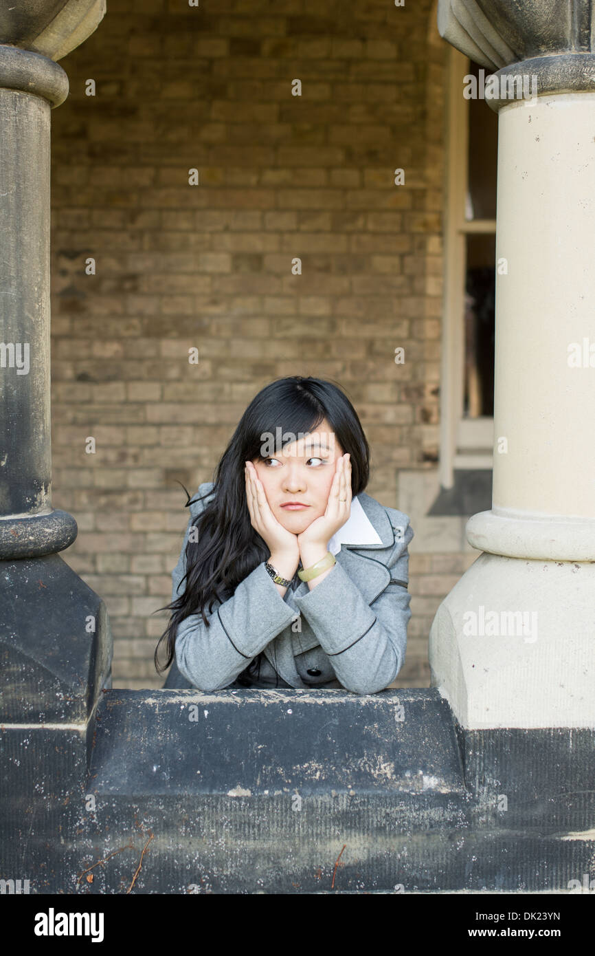 Young woman leaning forward next to stone pillars Stock Photo - Alamy
