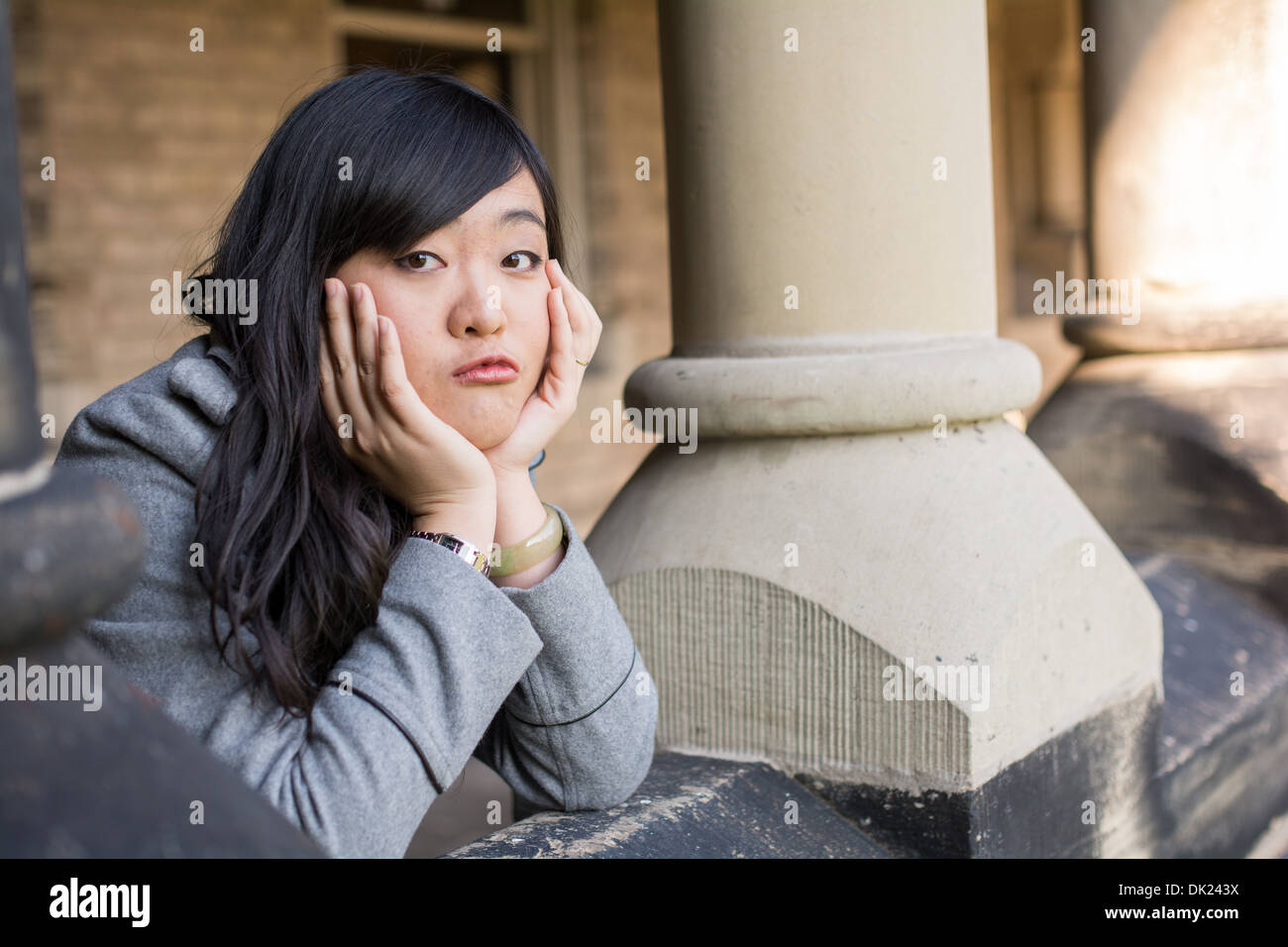 young woman leaning forward next to stone pillars Stock Photo - Alamy