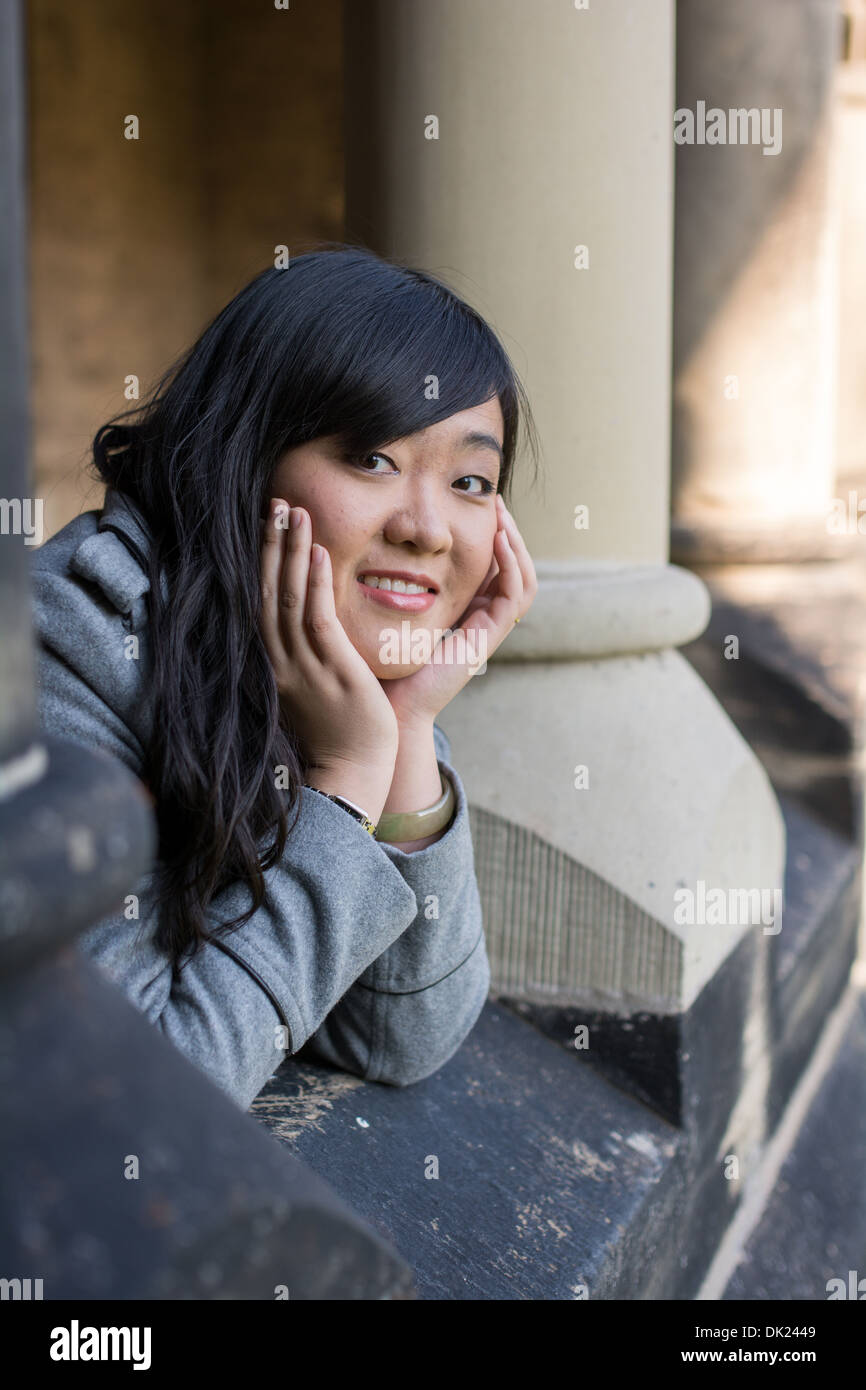 young woman leaning forward next to stone pillars Stock Photo - Alamy