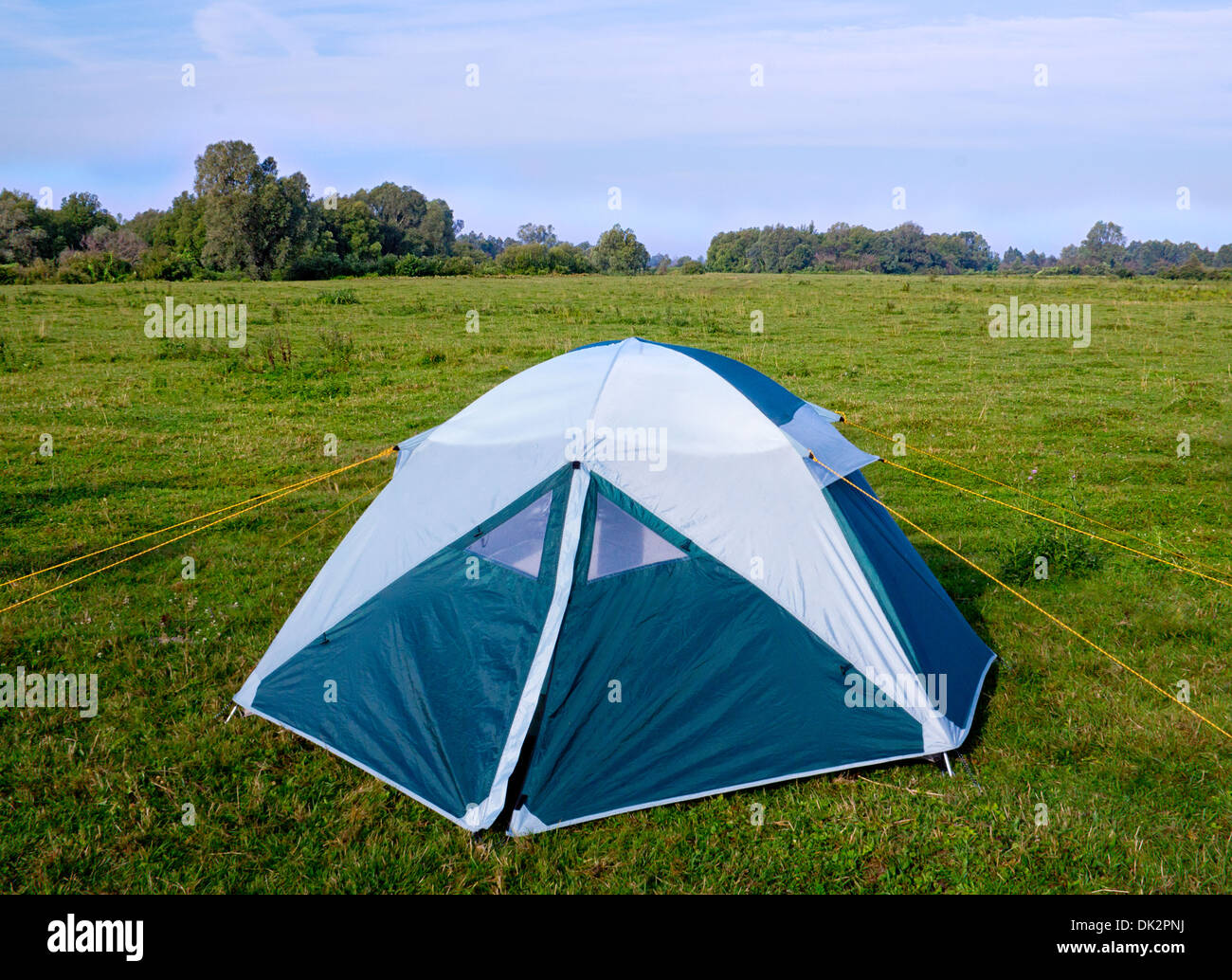 Practical single camping tent of blue-white color on the green meadow ...