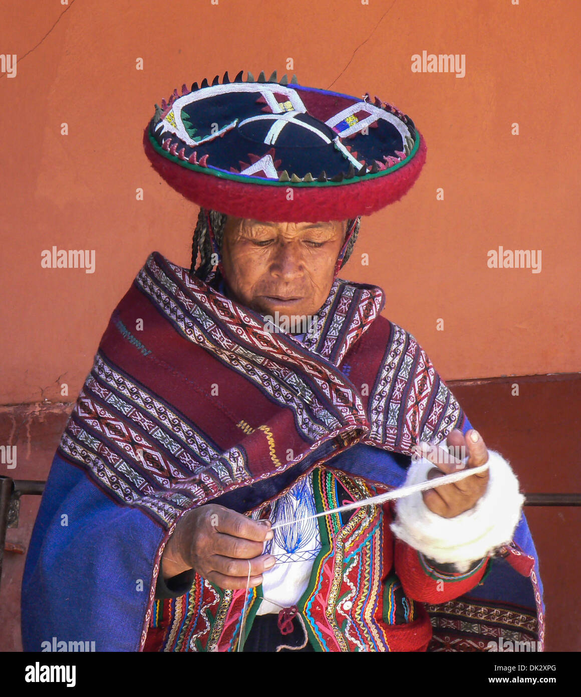 A native Peruvian Indian dressed in traditional costume spinning Alpaca ...