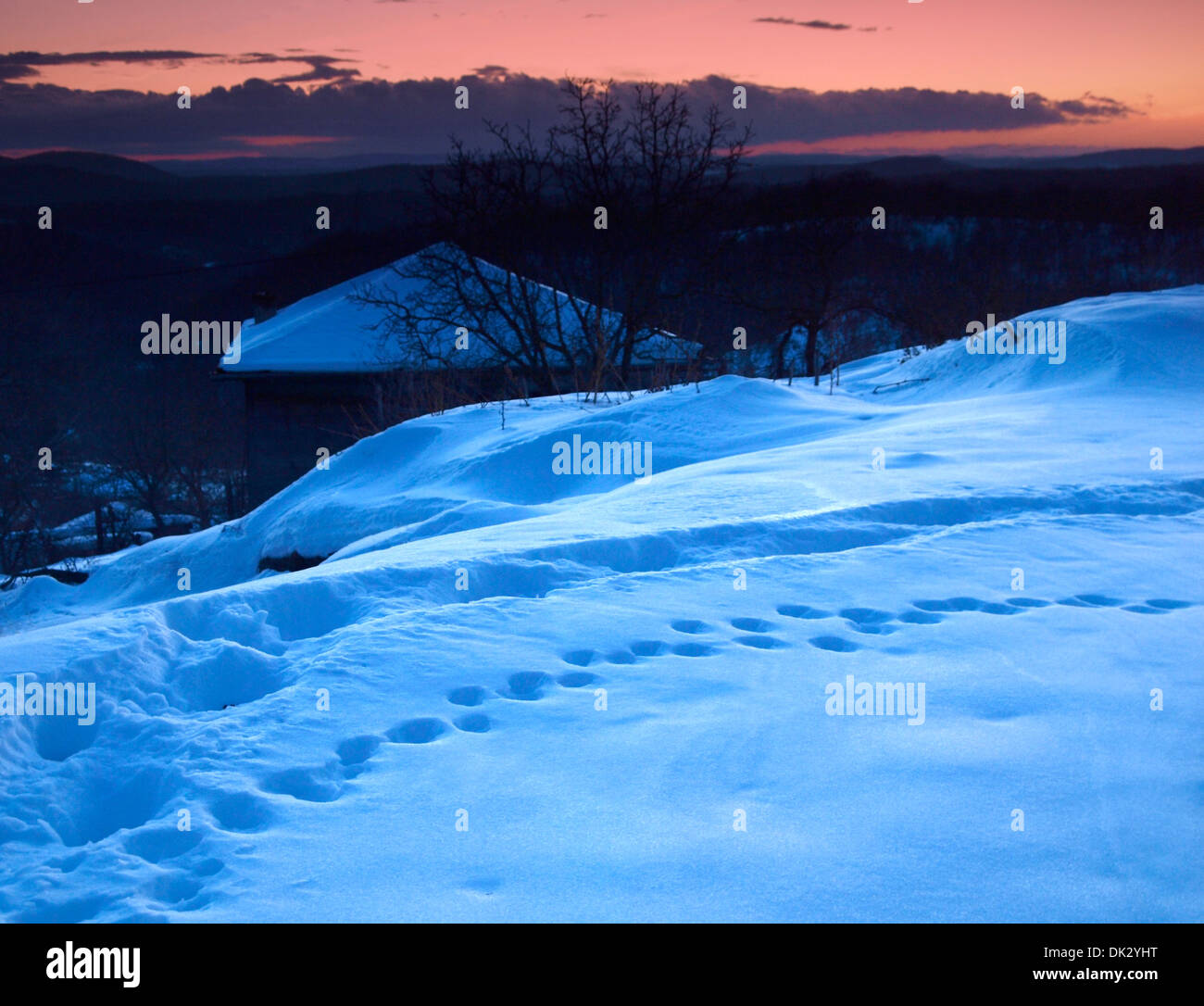 Small wooden cottage in the winter mountains covered with snow at dusk ...