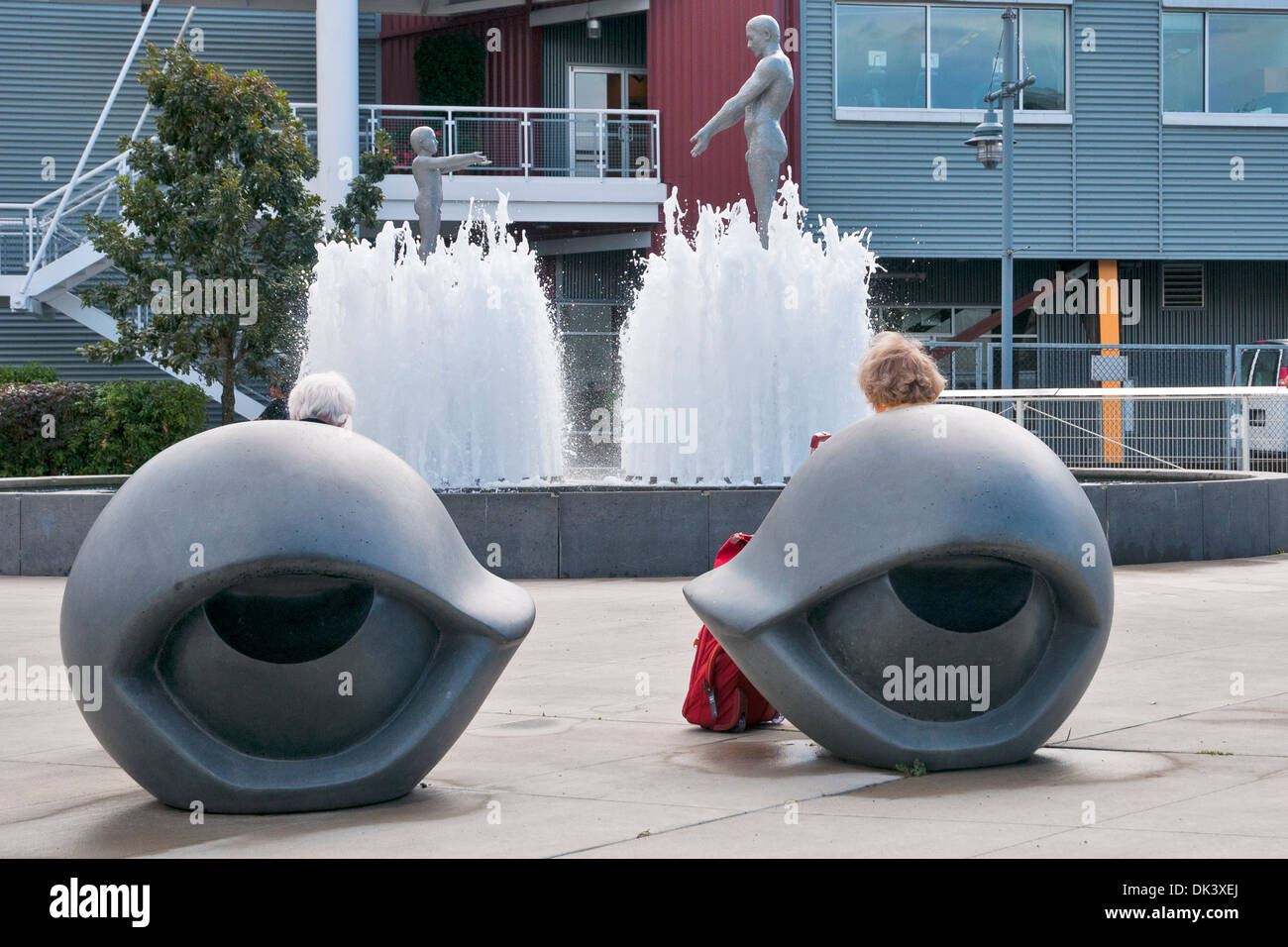 Two women sitting spherical benches sculpture and admire fountain ...