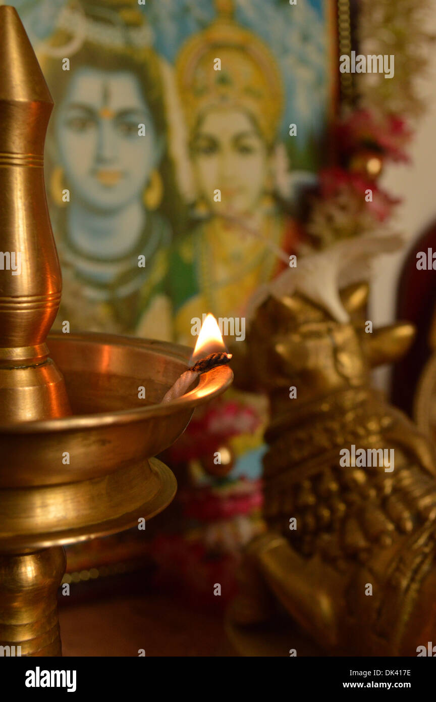 A Lighted brass Lamp in front of a portrait of Hindu Gods Stock Photo ...