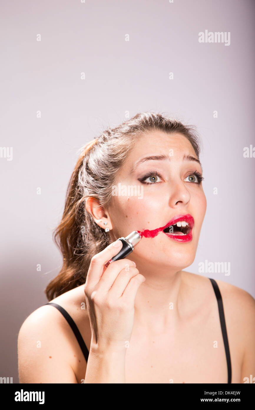 Young woman smears lipstick on her face Stock Photo - Alamy