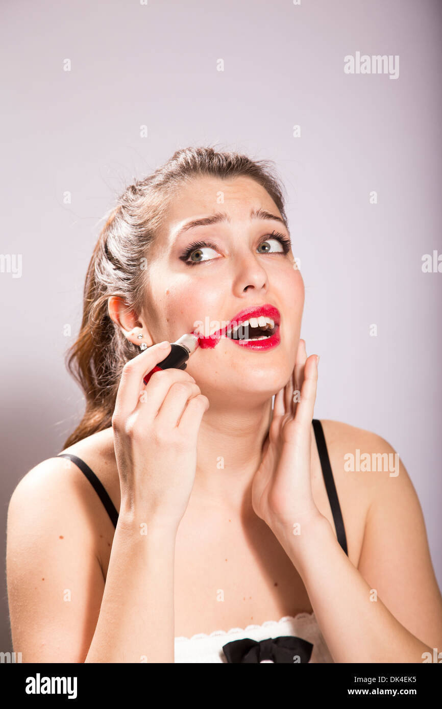 Young woman smears lipstick on her face Stock Photo - Alamy