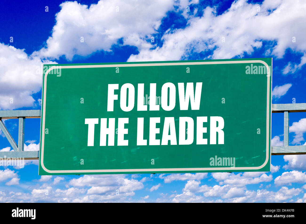 Fallow the leader sign on the green board with clouds in background ...