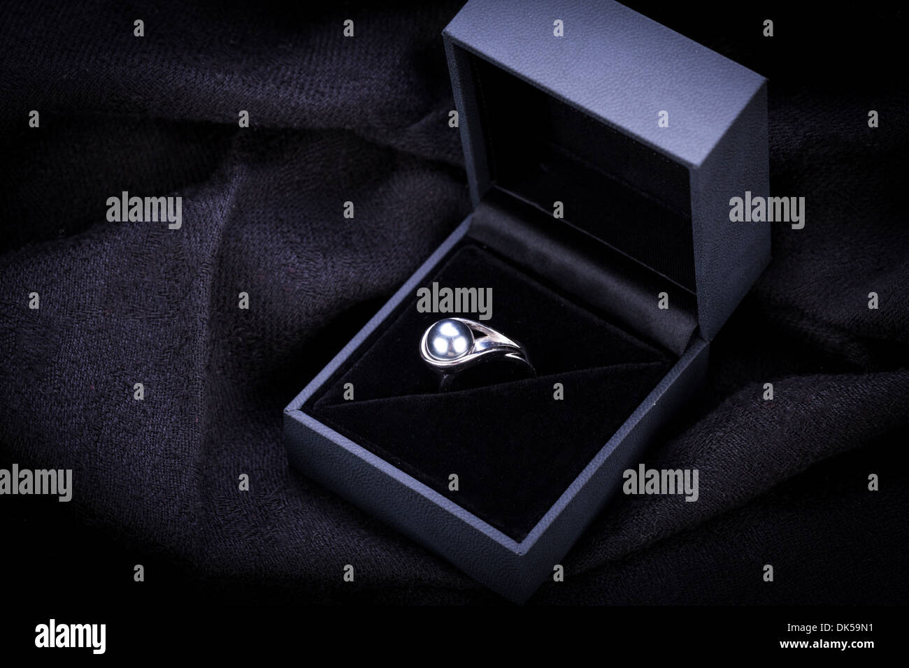 Dark mysterious image of a glowing diamond engagement ring displayed in ...