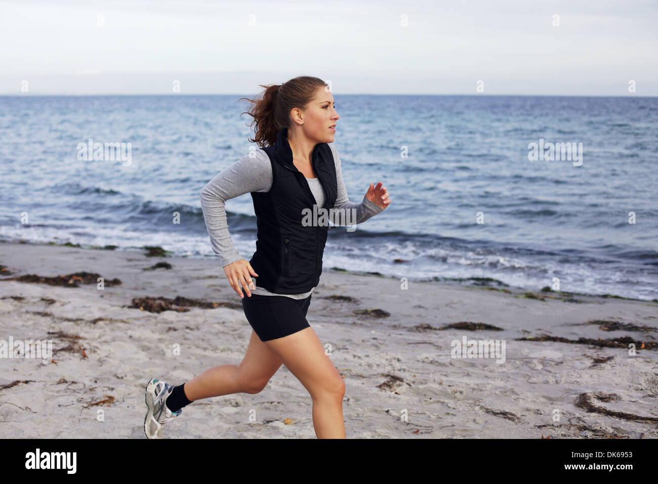 Female runner running on seashore. Woman jogging outside in sports ...