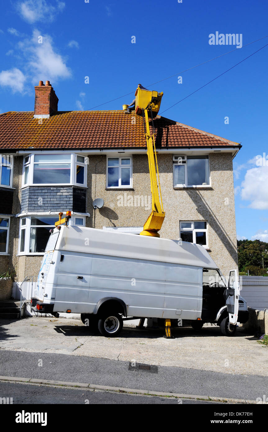 Roof repairs, workmen repairing roof with a "cherry picker" in Britain ...