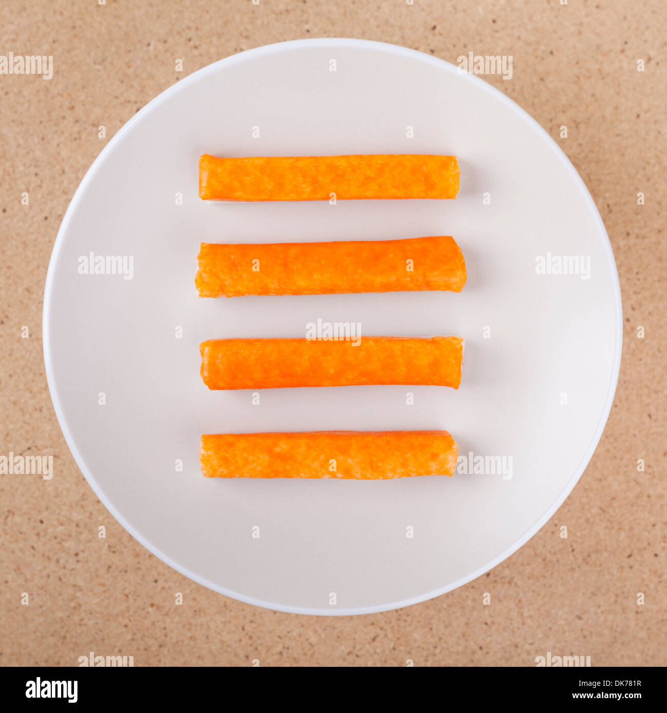 Four crab sticks on plate, over wooden background Stock Photo - Alamy
