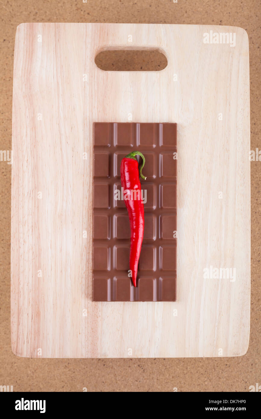 Fresh red hot chili pepper with chocolate on wooden chopping board ...