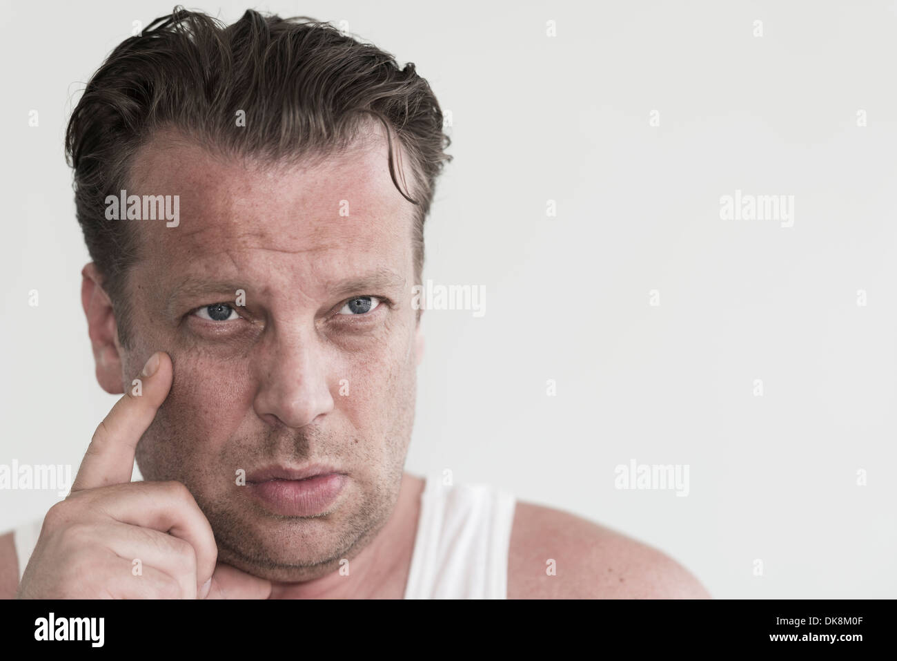 A Man With A Pensive Look And His Finger Against His Cheek On A White ...