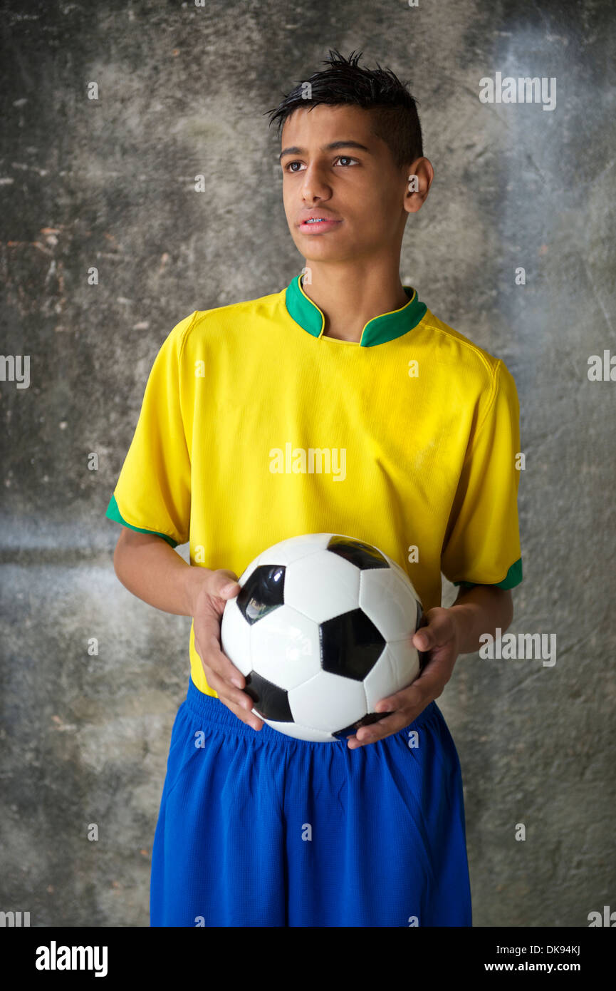 Young Brazilian soccer player in team uniform of Brazil colors holds ...