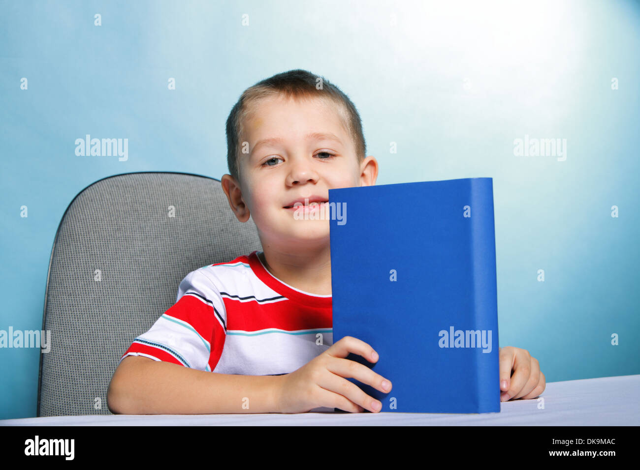 Young boy reading a book, child kid on blue background holding an open ...