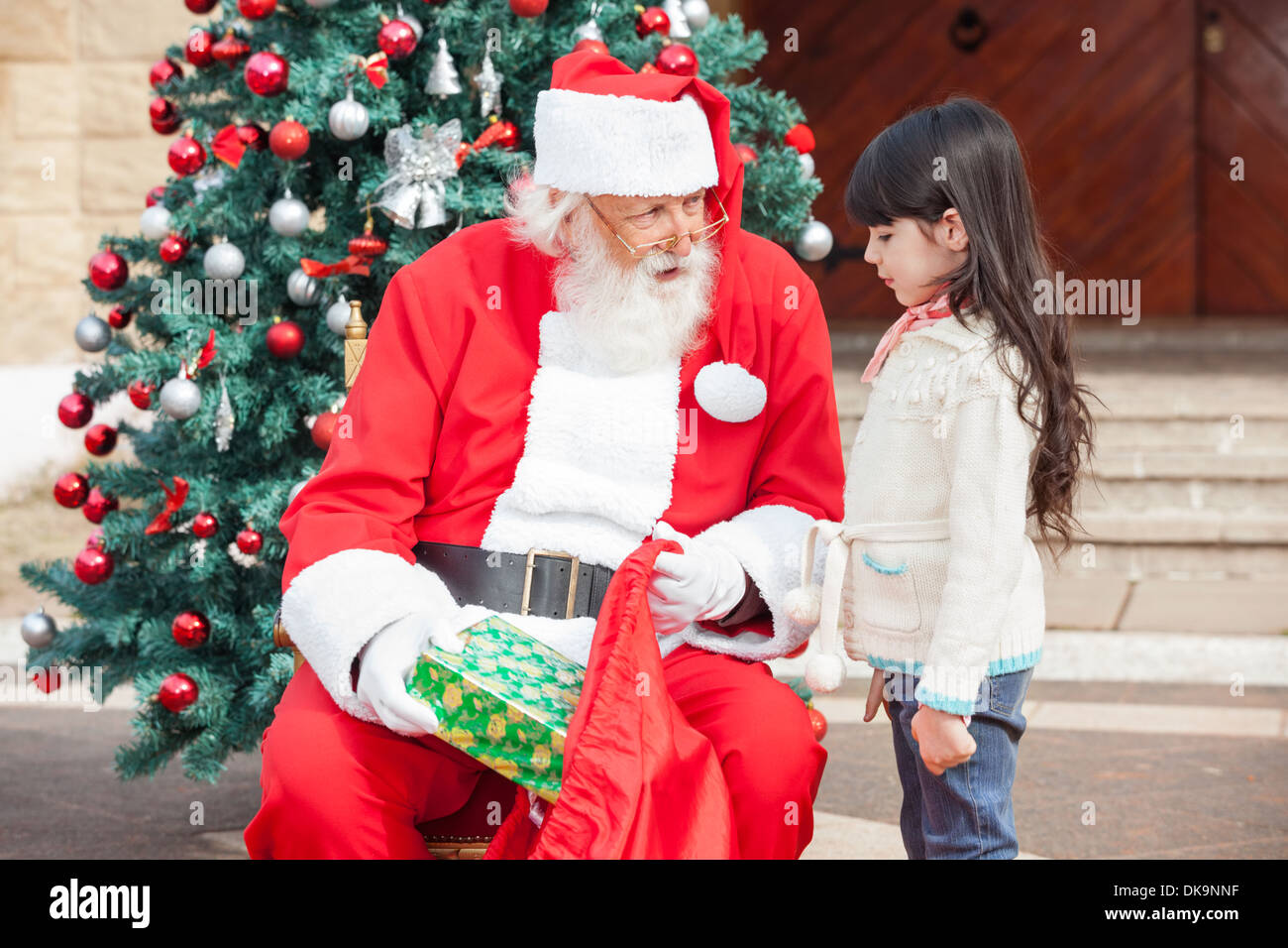 Santa Claus Giving Gift To Girl Stock Photo - Alamy
