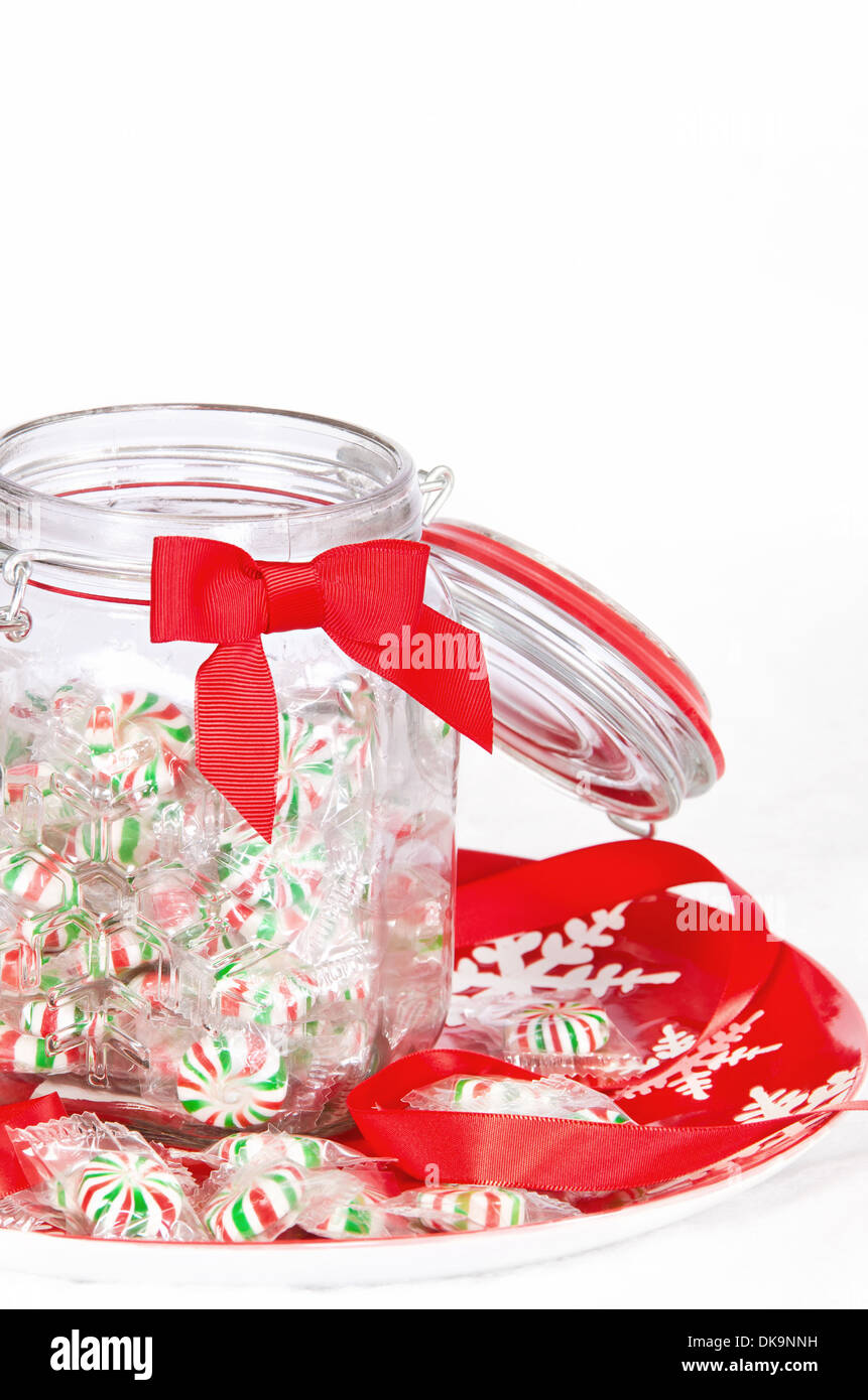 Pinwheel Christmas candies in a glass jar, displayed on red holiday ...