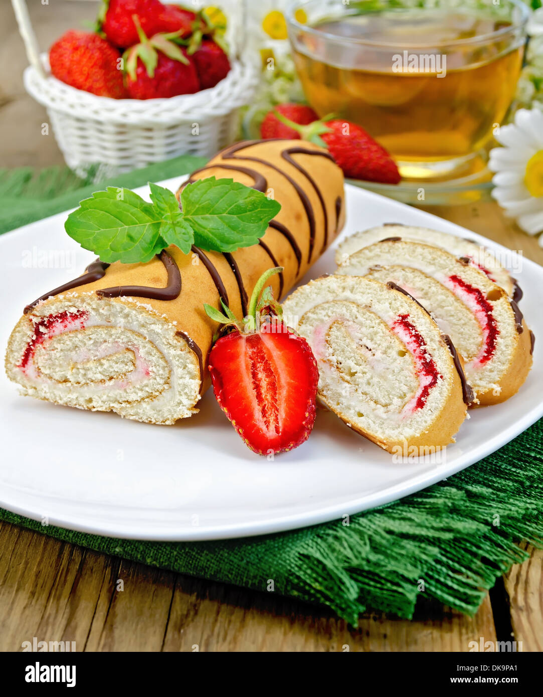 Biscuit roulade with cream and jam, glass cup with tea, cloth ...