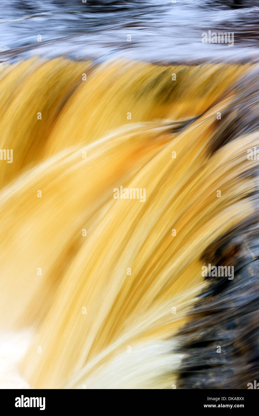 Smooth falling water of a yellow natural waterfall Stock Photo - Alamy