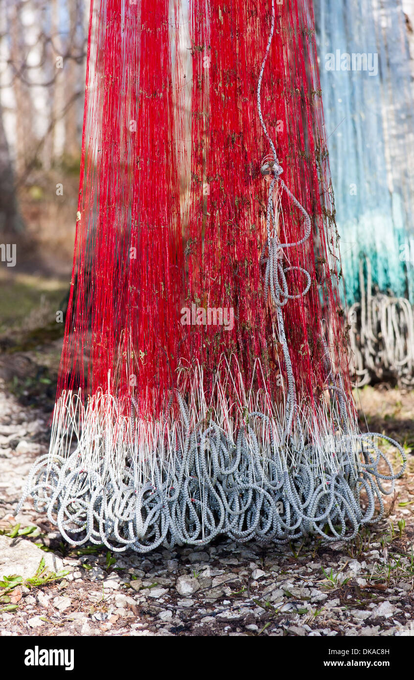 Hanging dirty red fishing net. Greenish net at the left side on ...