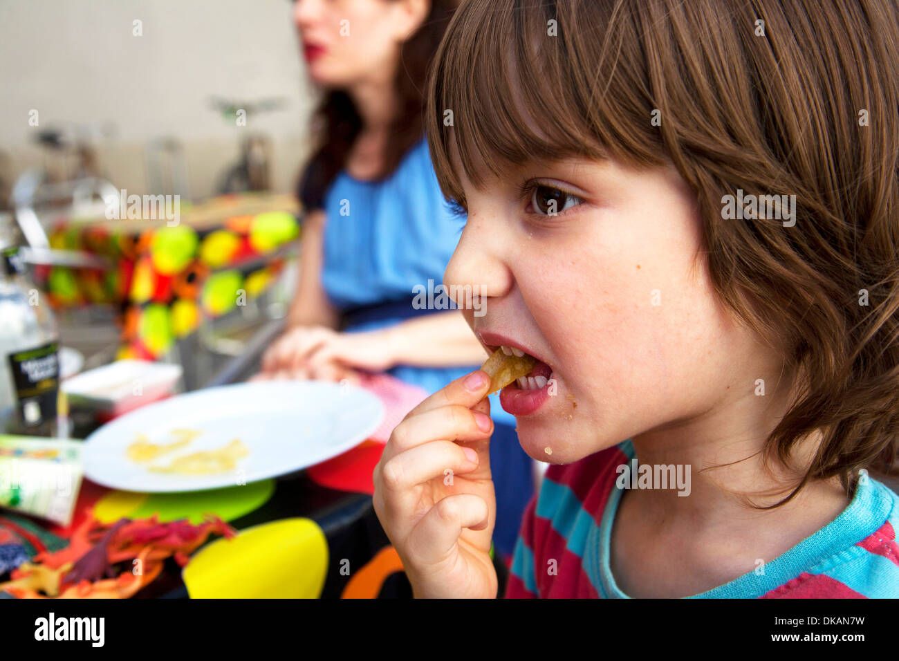 5 year old boy eating crisps at outside table Stock Photo - Alamy