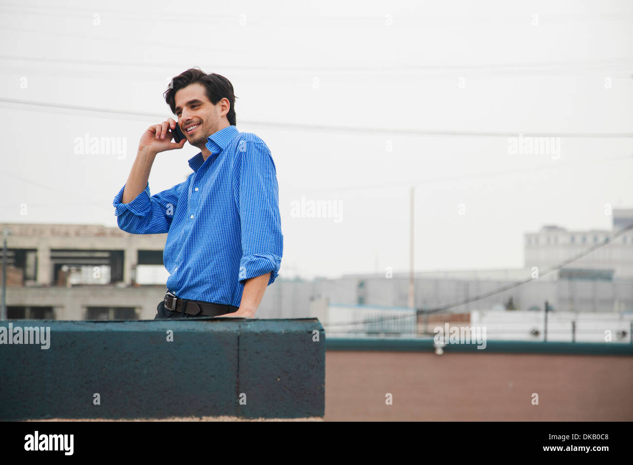 Confident young man using mobile on city rooftop Stock Photo - Alamy