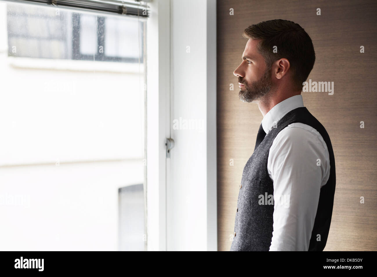 Portrait of businessman looking out of window Stock Photo - Alamy