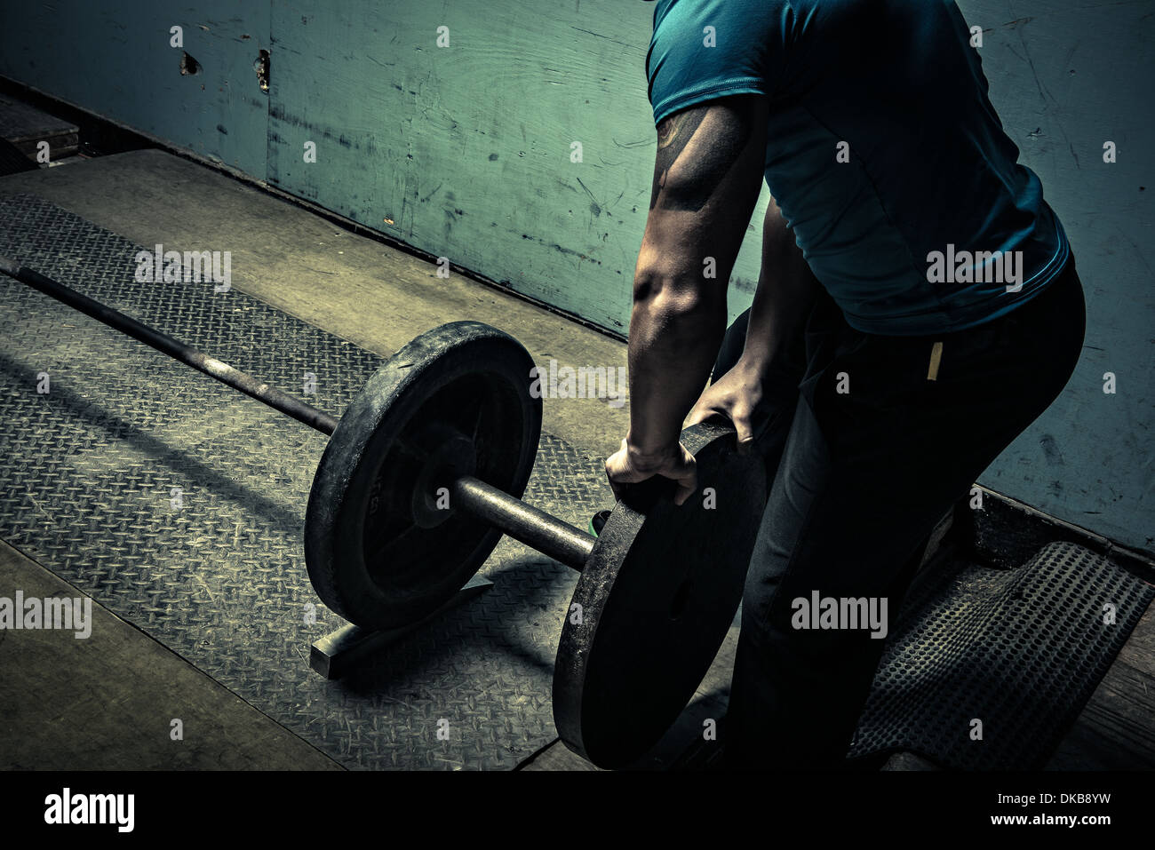 Weightlifter in dark gym, kneeling down Stock Photo - Alamy