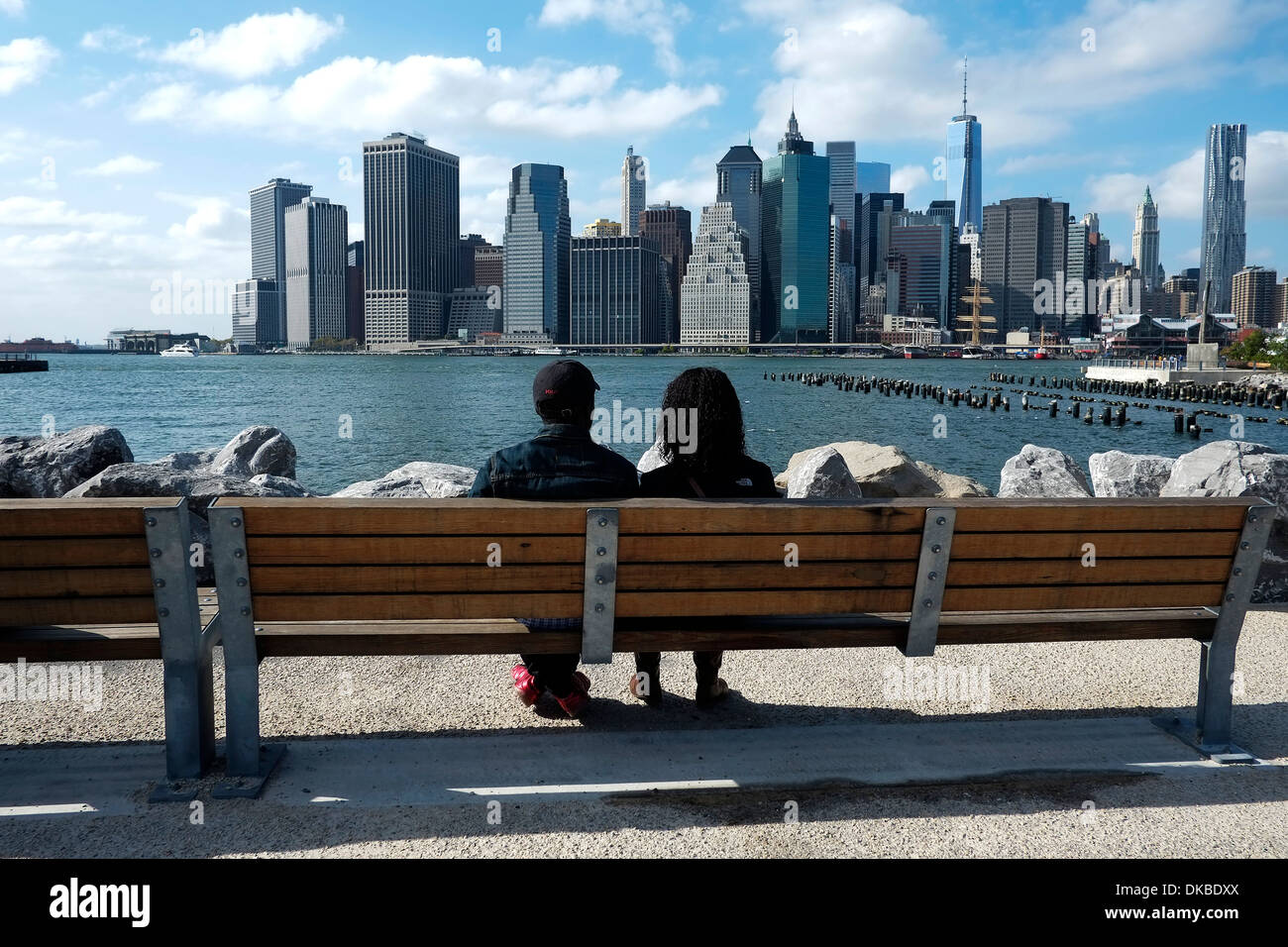 Two people on a bench with a view of lower Manhattan from Brooklyn ...