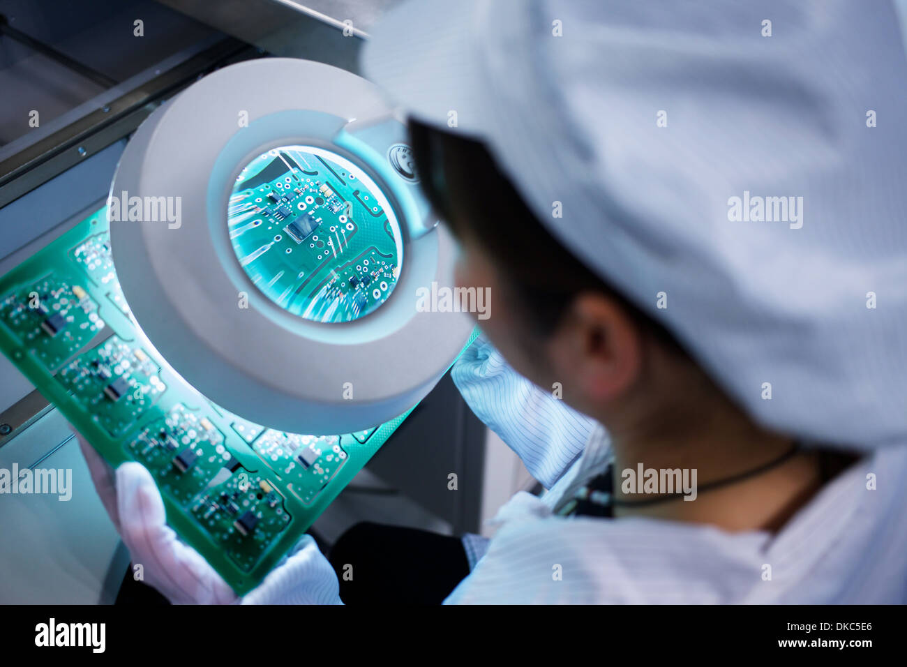 Worker at small parts manufacturing factory in China looking through ...