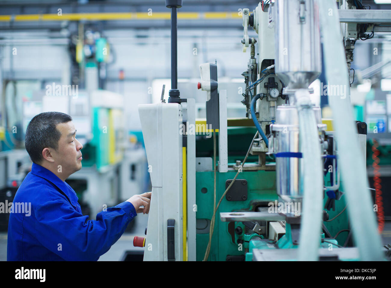 Worker at small parts manufacturing factory in China, pressing button ...