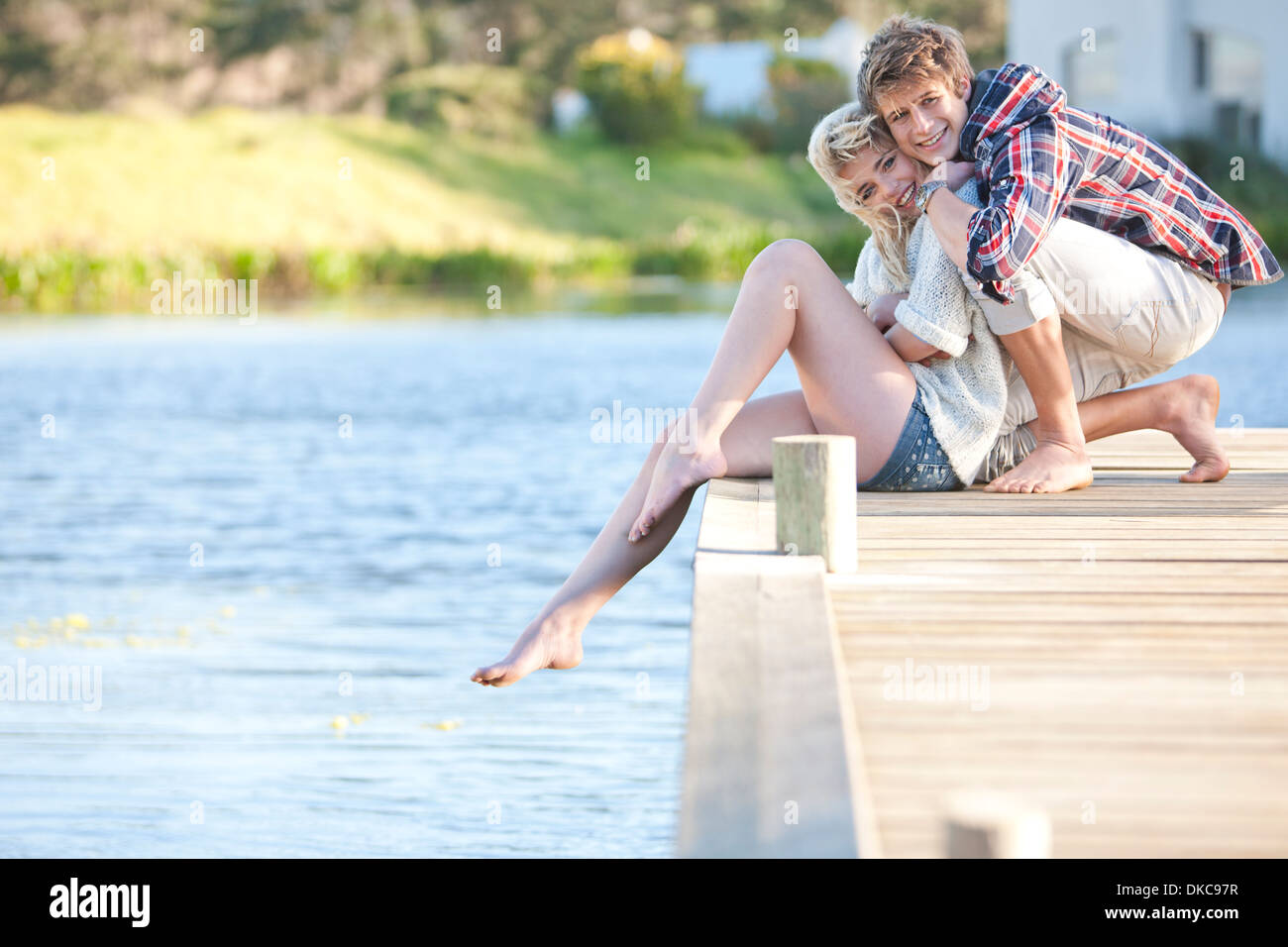 Young romantic couple sitting on pier Stock Photo - Alamy