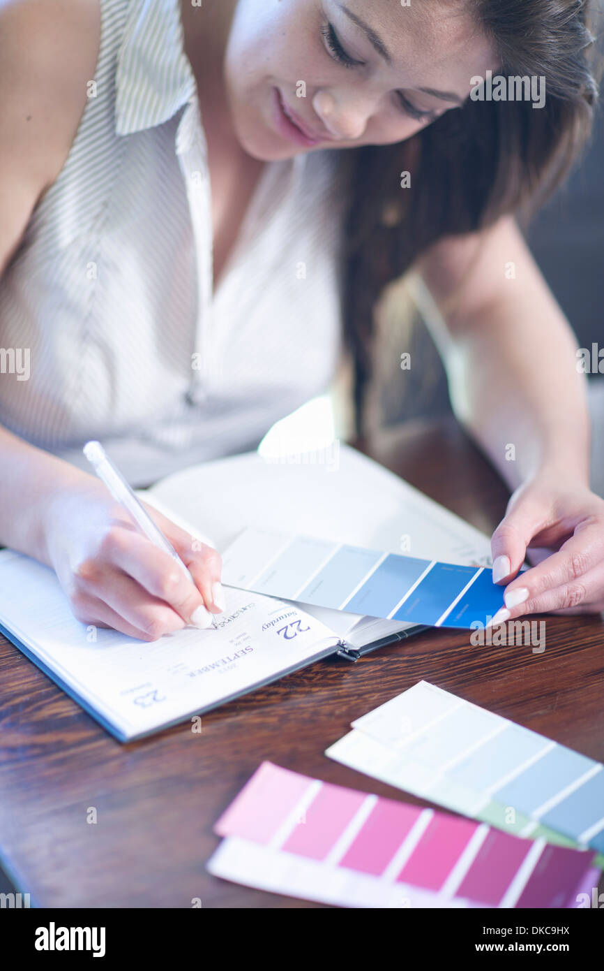 Interior designer with swatches writing in diary Stock Photo - Alamy