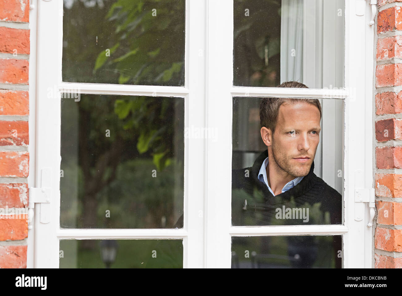 Mid adult man looking out of window Stock Photo - Alamy