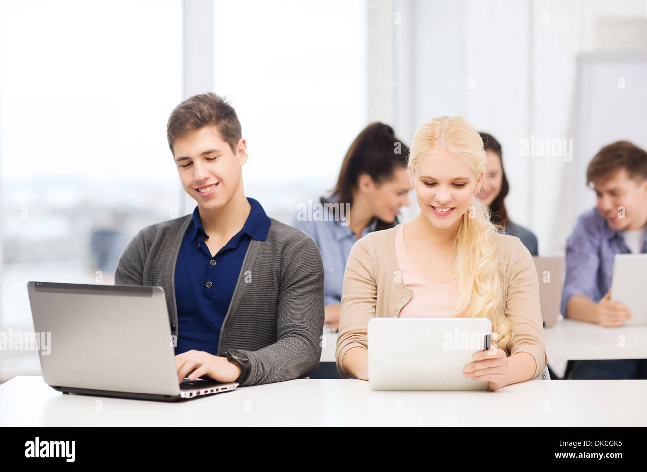 two smiling students with laptop and tablet pc Stock Photo - Alamy