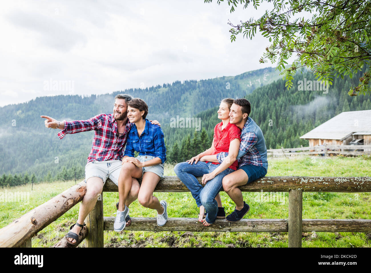 Four friends sitting on fence, Tyrol Austria Stock Photo - Alamy