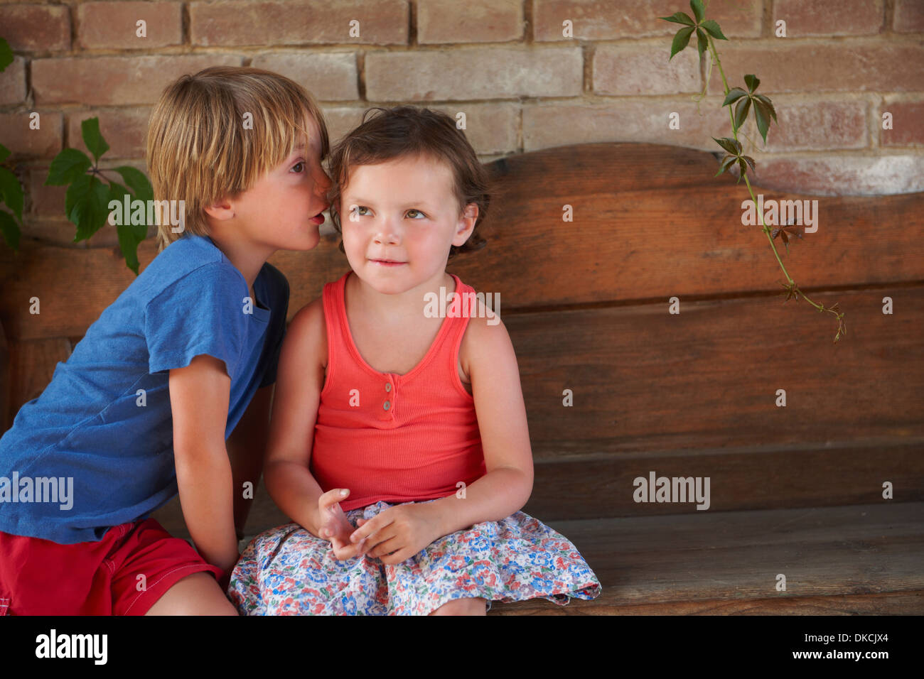 Boy whispering into girl's ear Stock Photo - Alamy