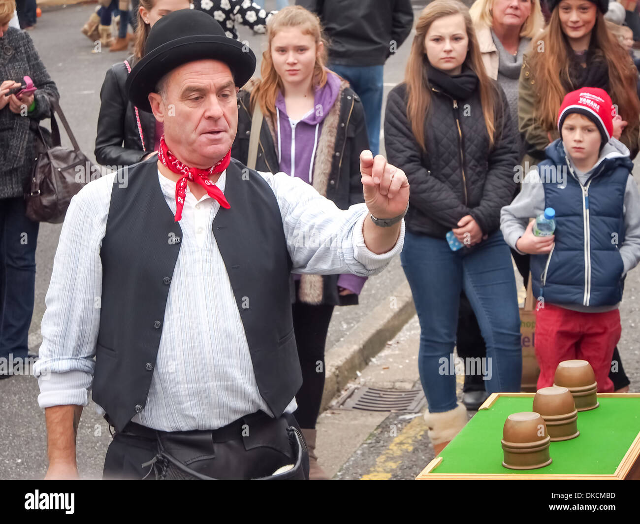 A street performer demonstrating the three cups and ball trick to ...