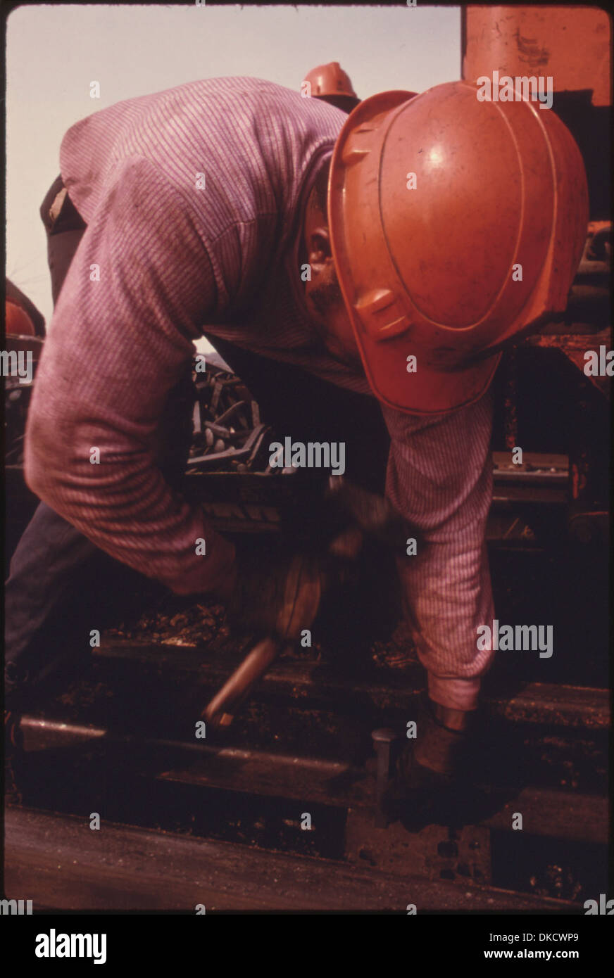 This image shows a Southern Railway worker driving a railroad spike ...