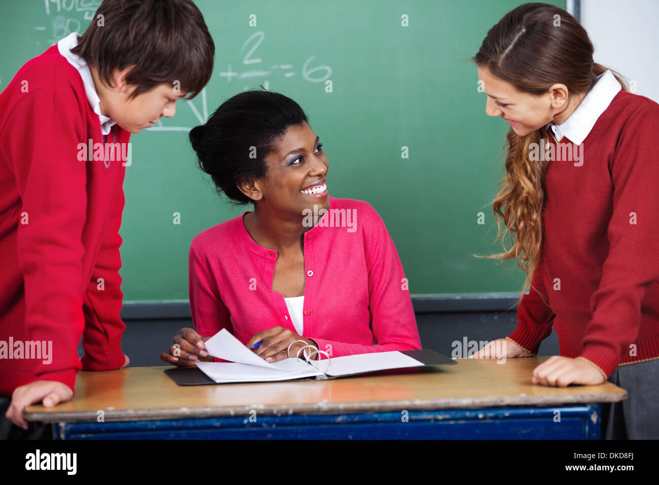 Teacher Discussing With Students At Desk Stock Photo - Alamy