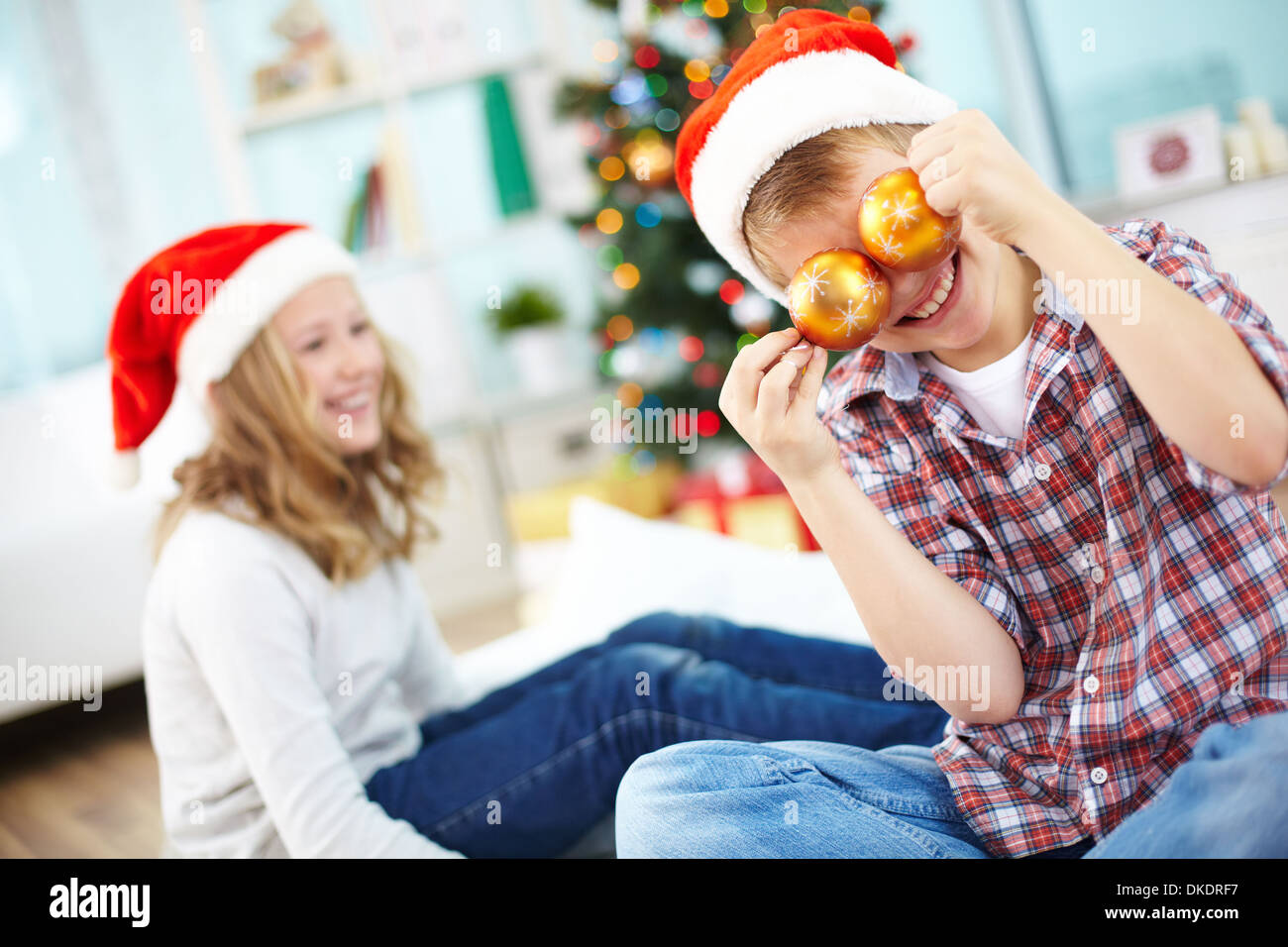 Portrait of happy lad holding decorative toy balls by eyes with his ...