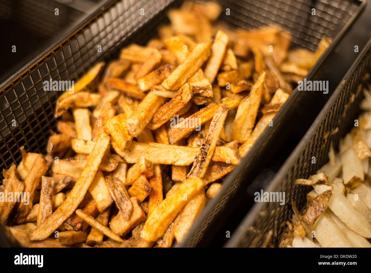 Golden brown French fires in the fryer, freshly cooked chips ready to ...