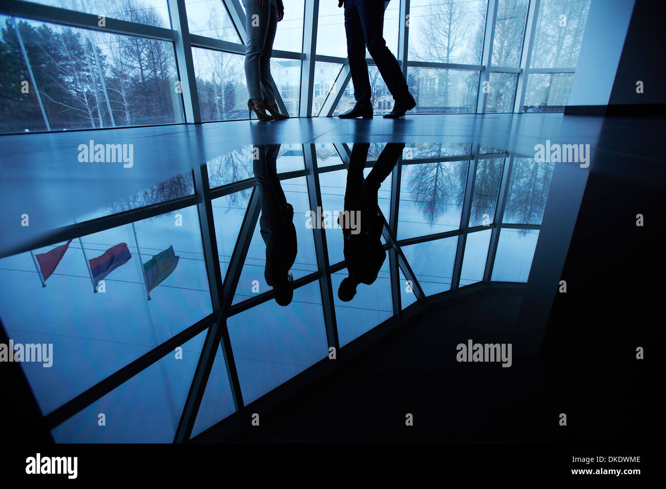Legs of businessman and businesswoman standing by the window in office ...