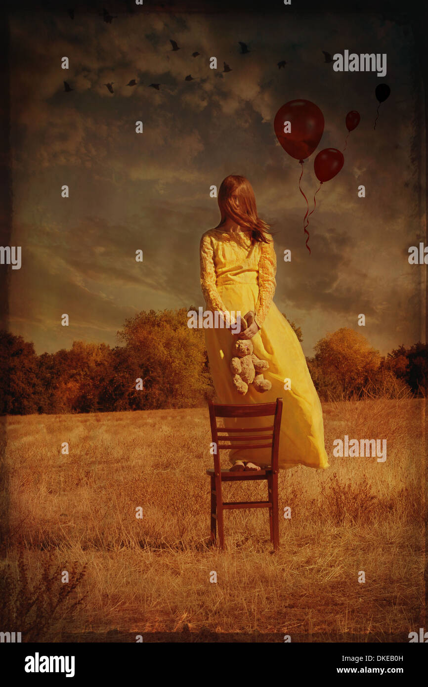 Girl standing on chair in field with red ballon Stock Photo - Alamy