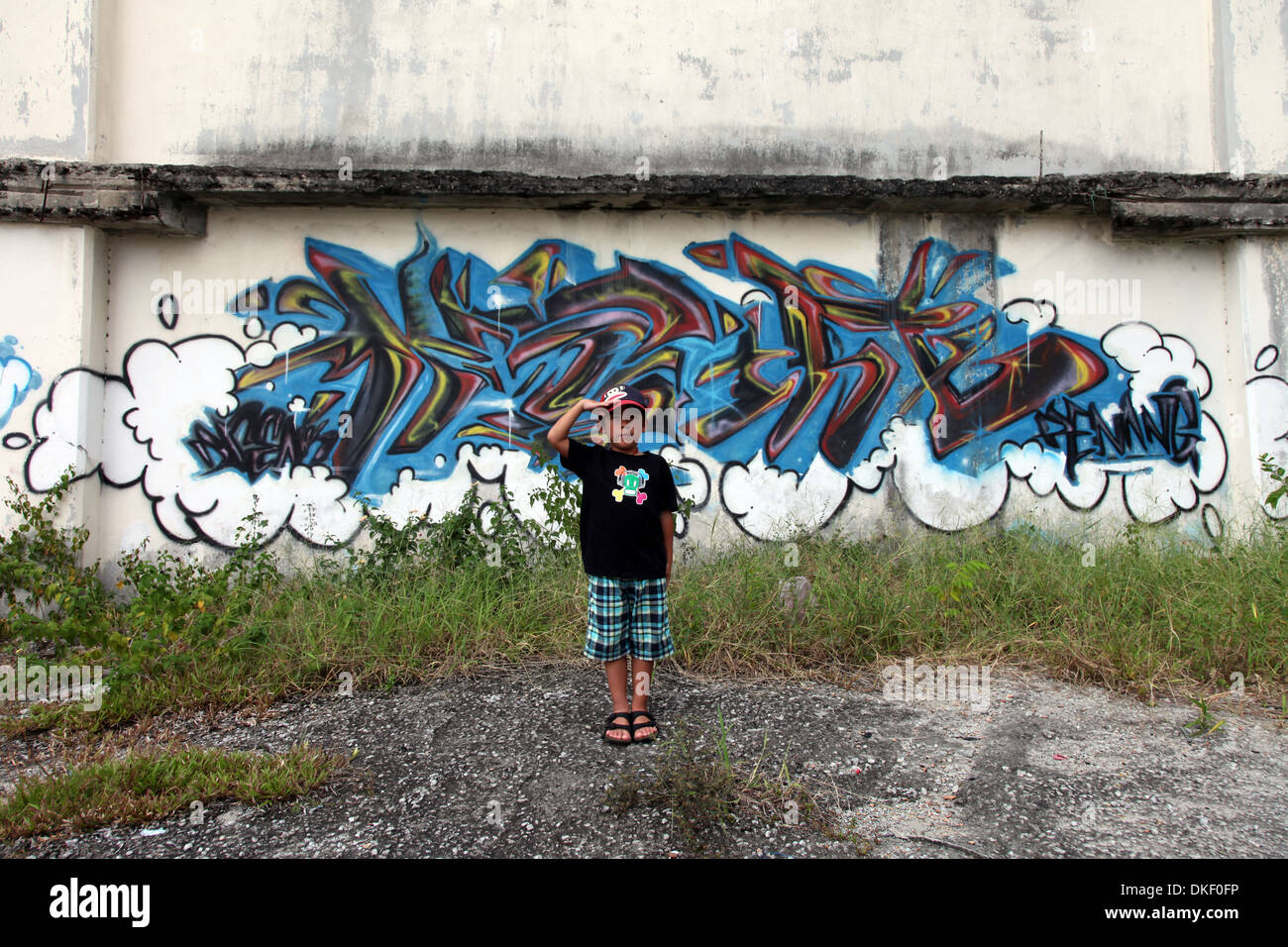 It's a photo of a little boy who is posing in front of graffiti in a no ...