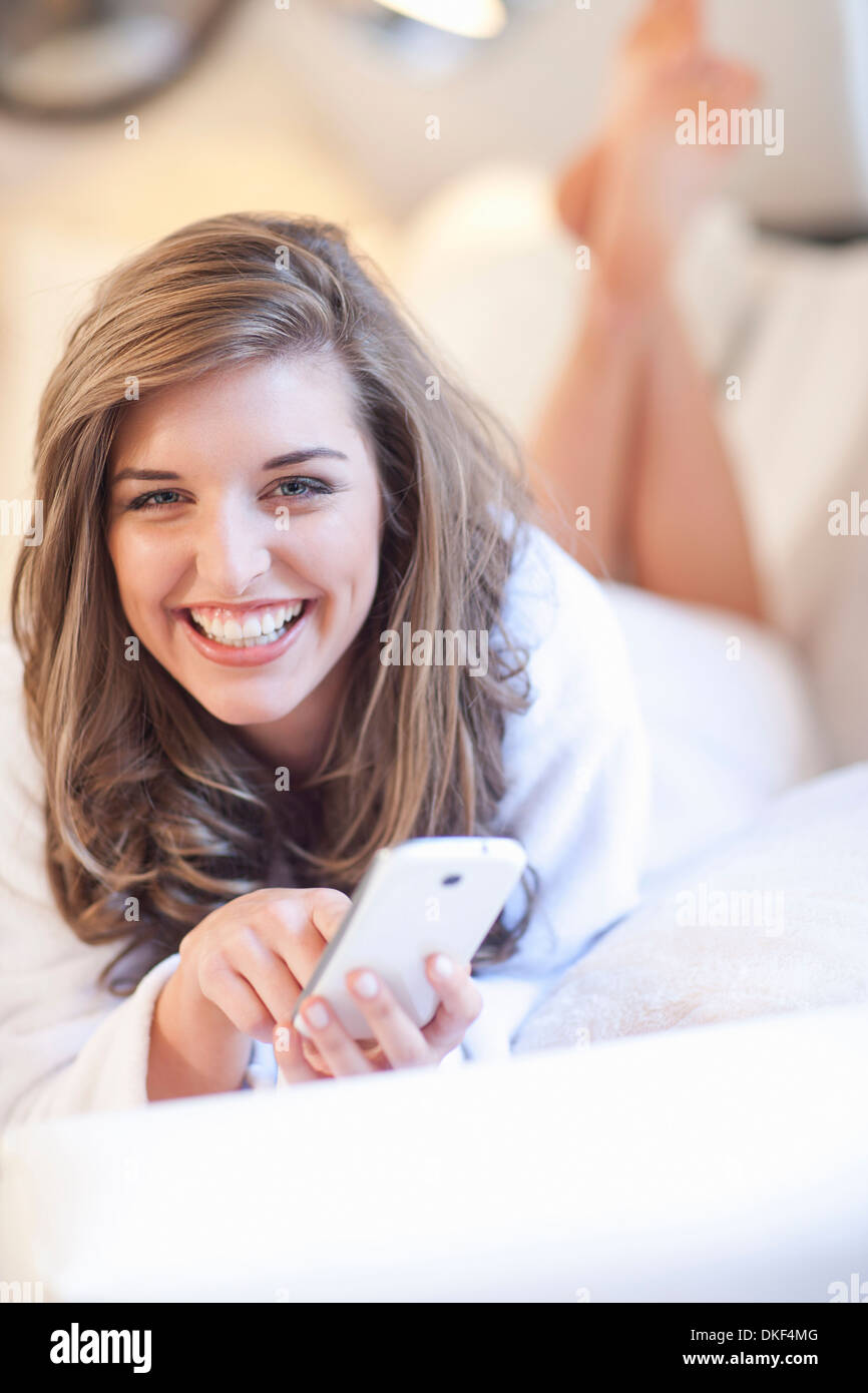 Portrait of young woman lying on bed with mobile phone Stock Photo - Alamy