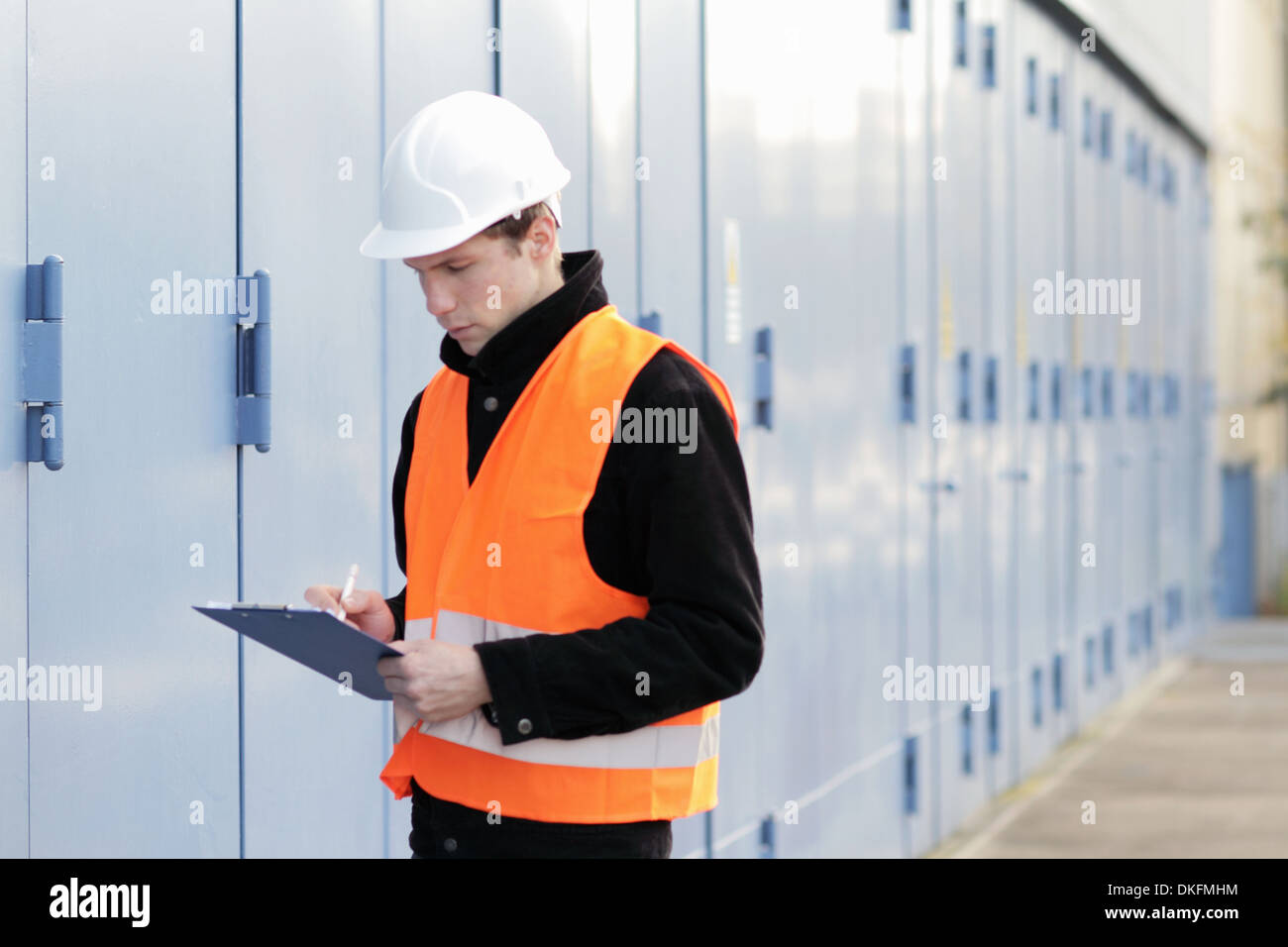 Builder writing paperwork using clipboard Stock Photo - Alamy