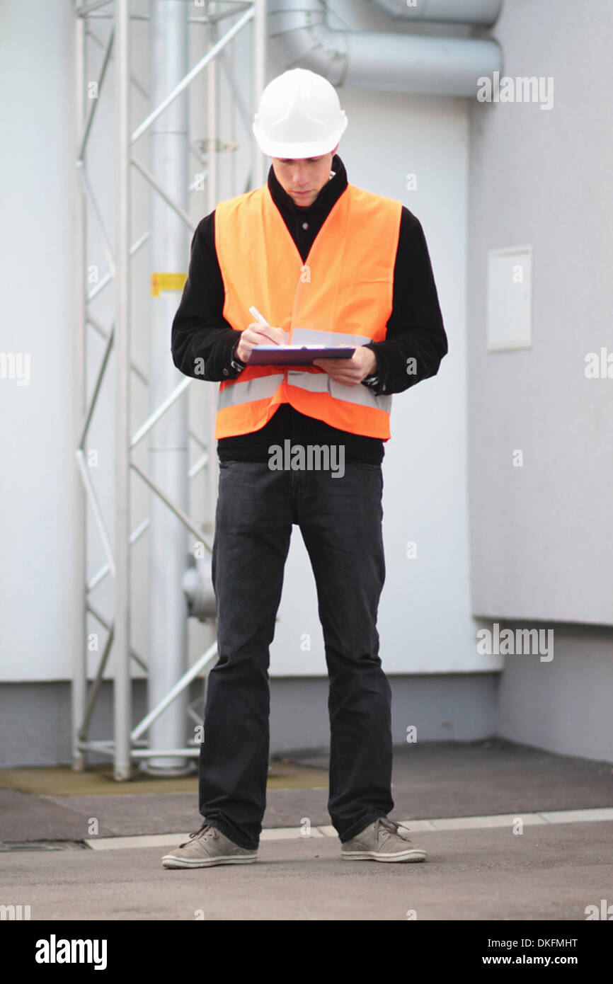 Builder writing paperwork using clipboard Stock Photo - Alamy