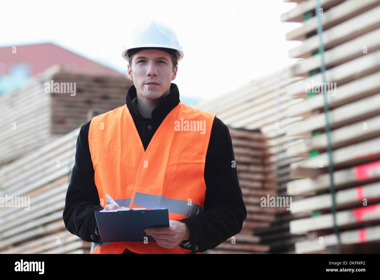 Builder writing paperwork using clipboard Stock Photo - Alamy