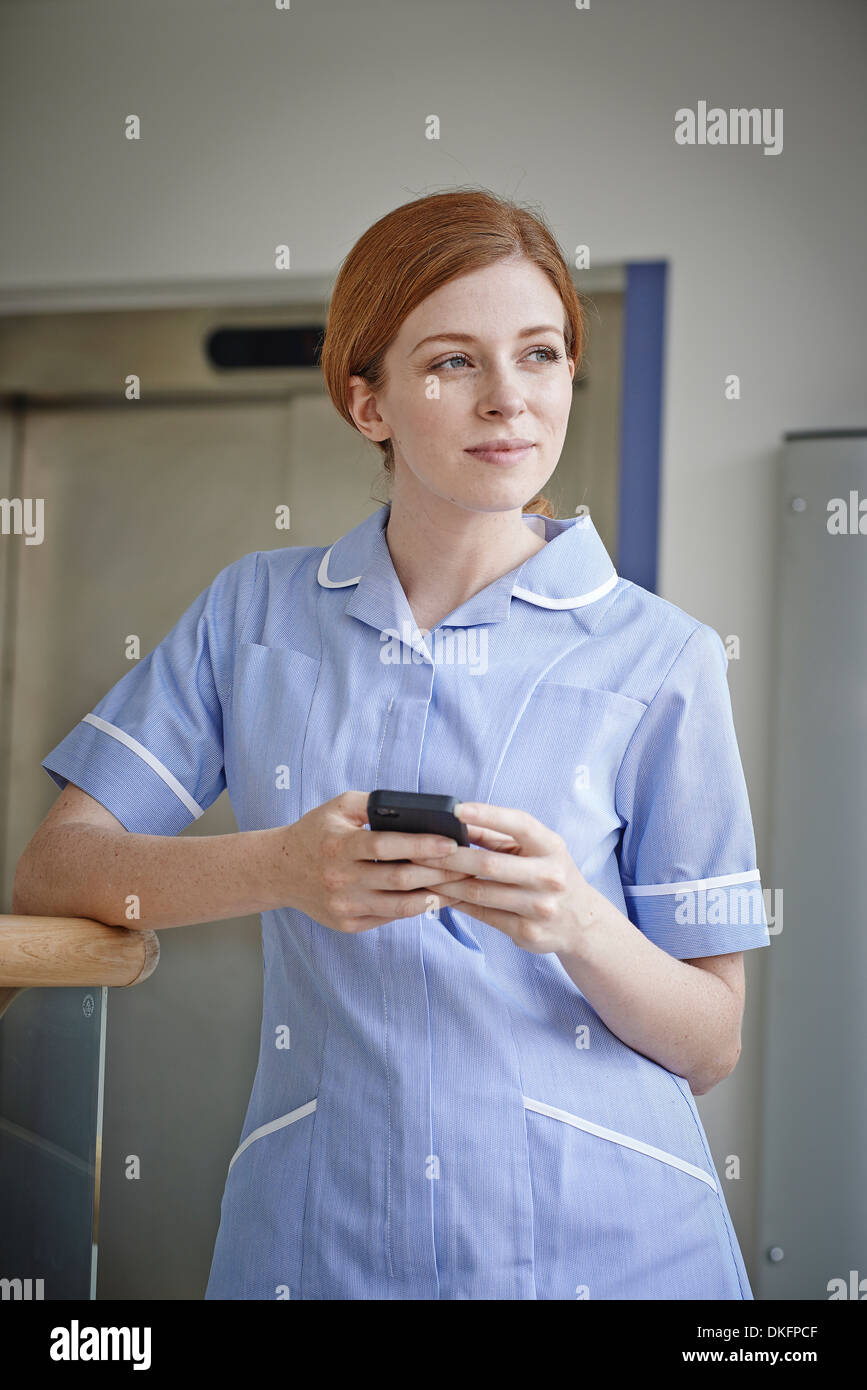 Female nurse with mobile phone outside hospital elevator Stock Photo ...
